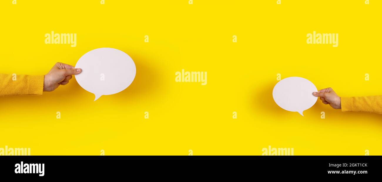 two talk bubbles speech icon in hand over yellow background, panoramic ...