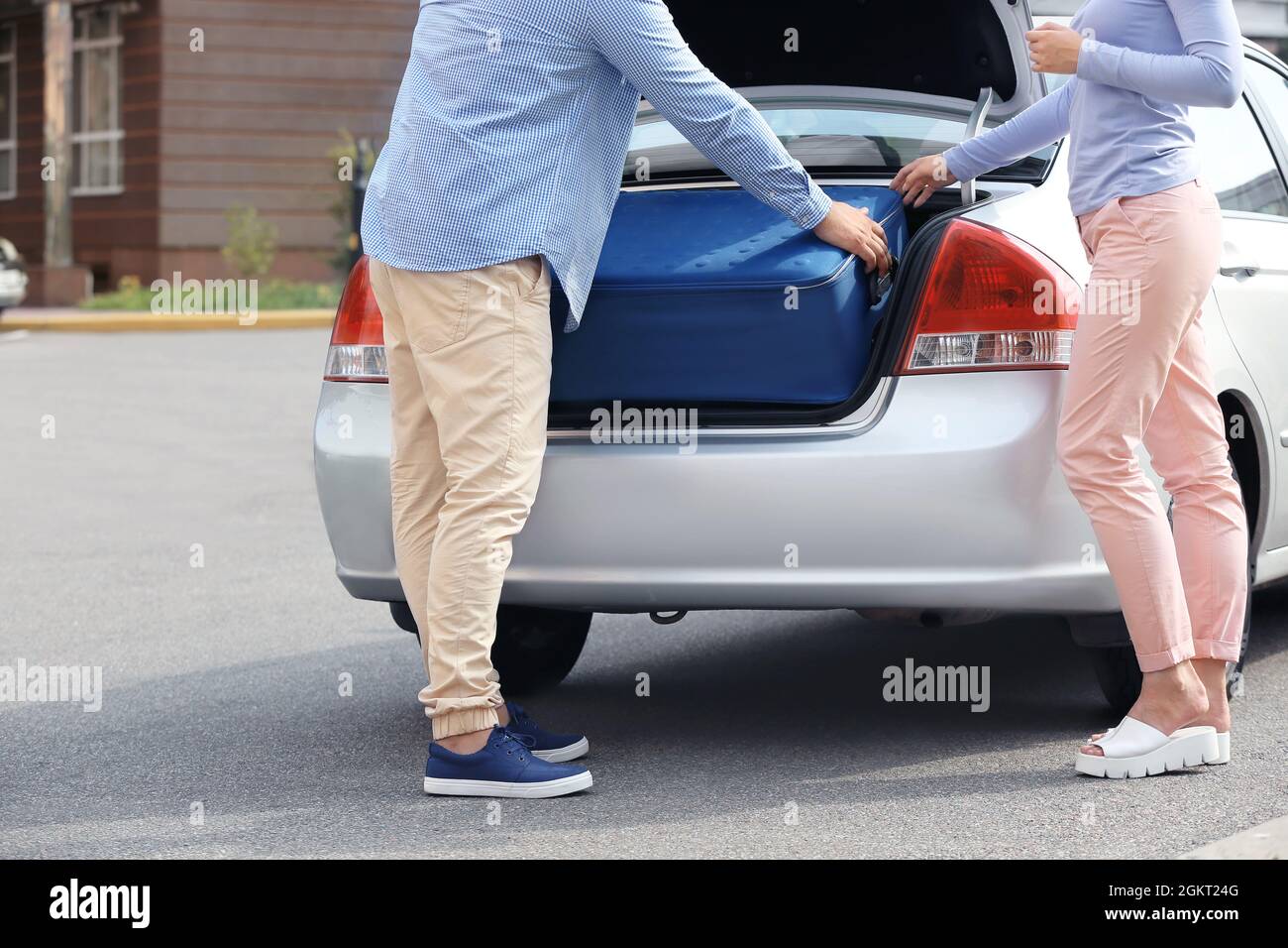 Taxi driver putting woman's suitcase in car trunk Stock Photo - Alamy