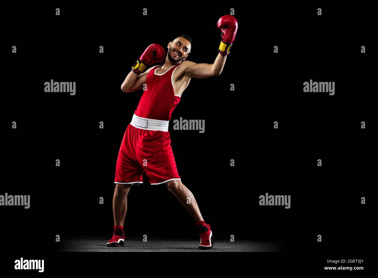 Full-length portrait of one professional boxer in red uniform training ...