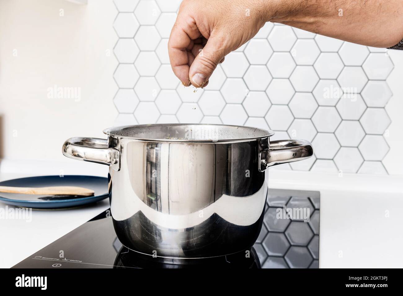 Chef's hand dressing the stew in the stainless steel pot that is on the ...