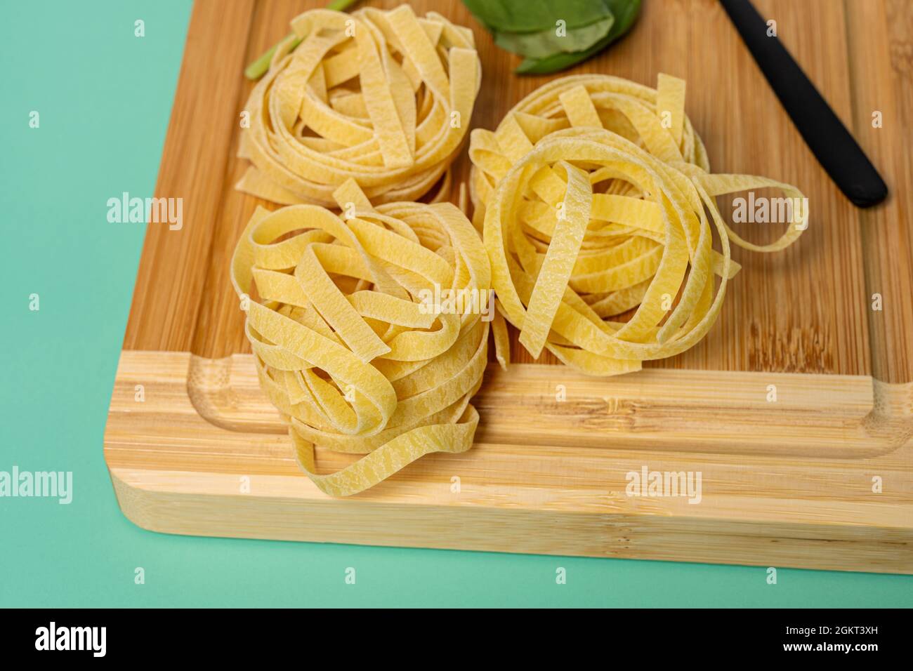 Italian fresh pasta nests on a bamboo table and green background Stock ...