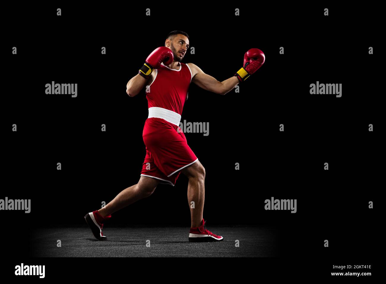 Full-length portrait of one professional boxer in red uniform training ...