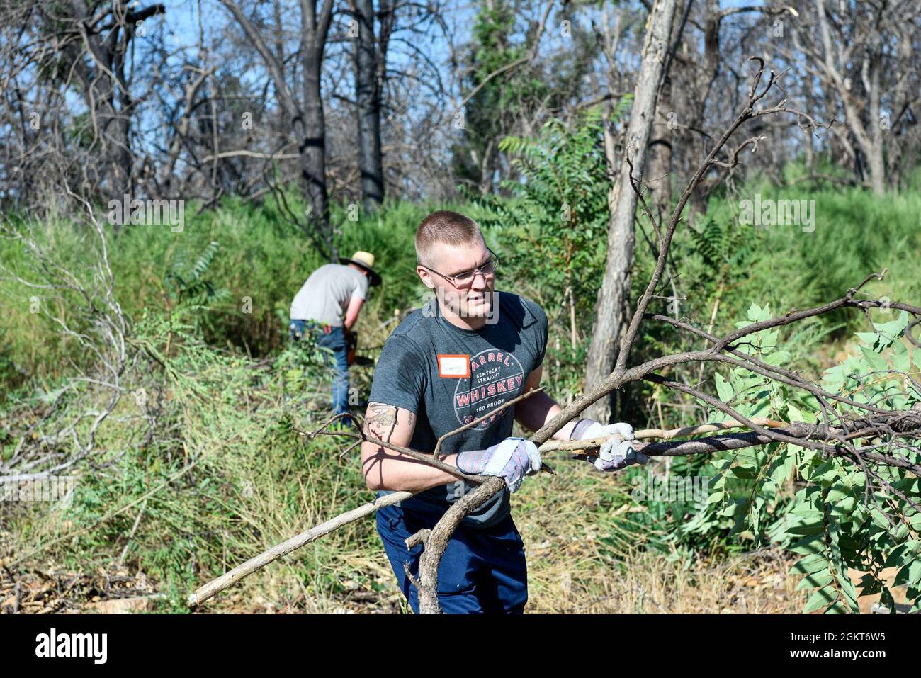 An Airman from Beale Air Force Base works to clear branches and brush ...