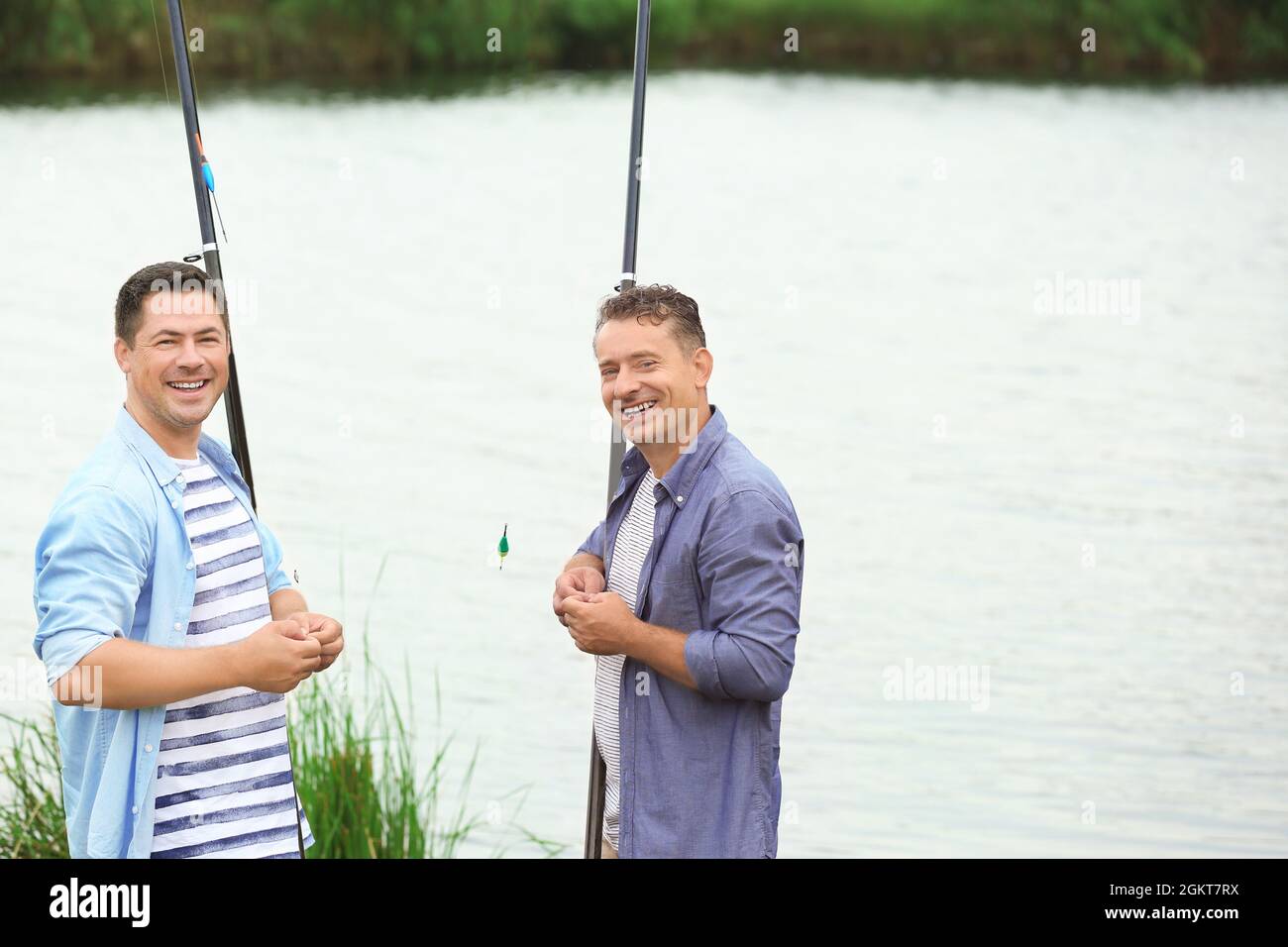 Men fishing from shore on river Stock Photo - Alamy