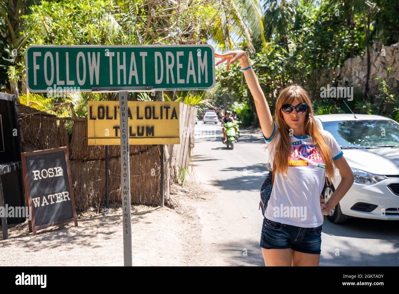 Beautiful female tourist showing motivational sign at roadside Stock ...