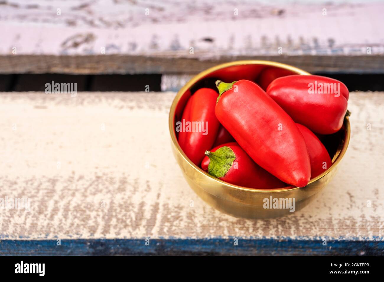 Raw red peppers inside a bowl that is on cream colored wooden boards ...