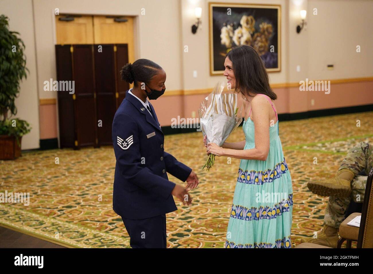 Staff Sgt. Thompson proffers a bouquet of red roses to the spouse of Lt ...