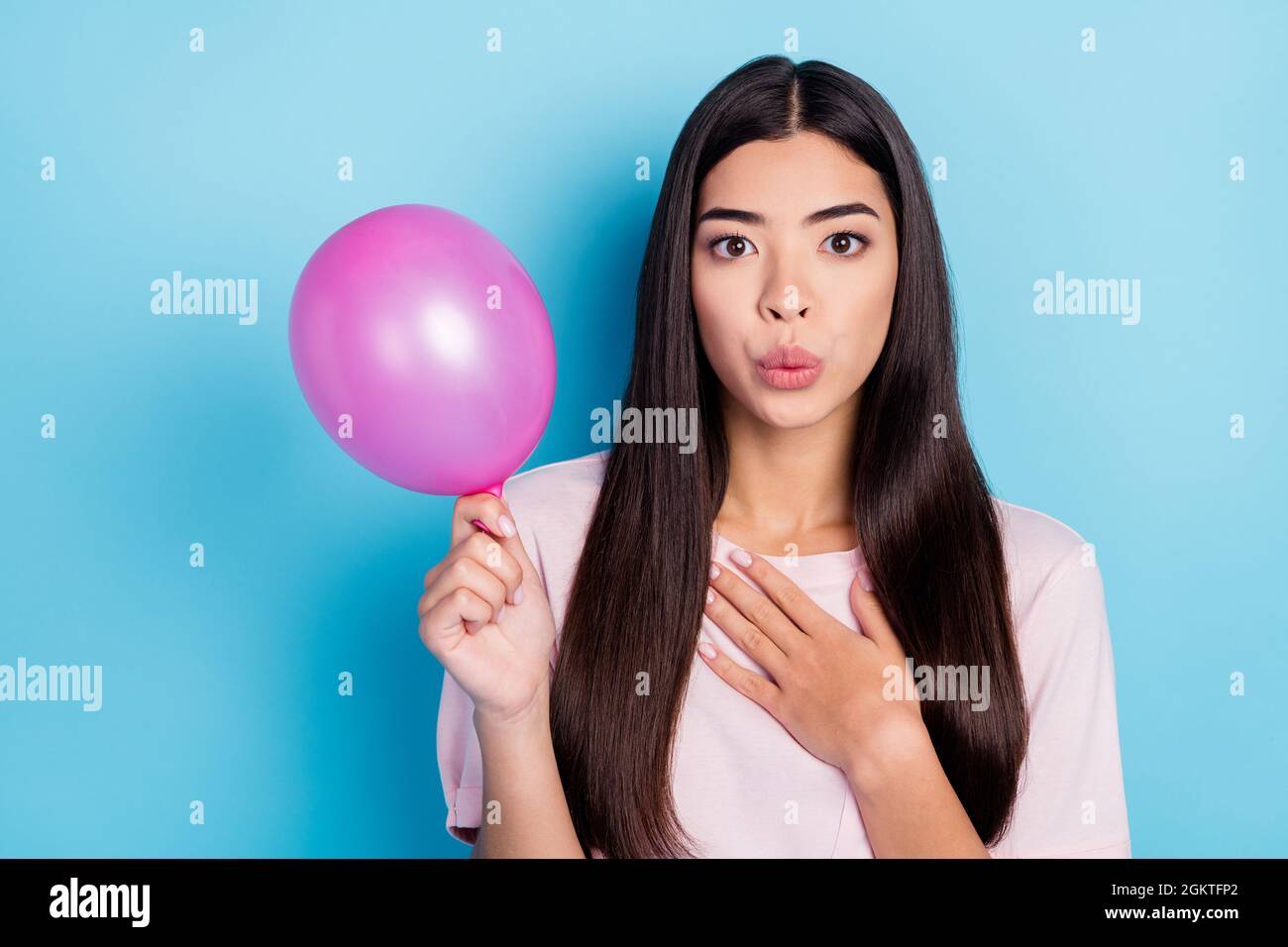 Photo of charming young amazed woman hold hand balloon chest festive ...
