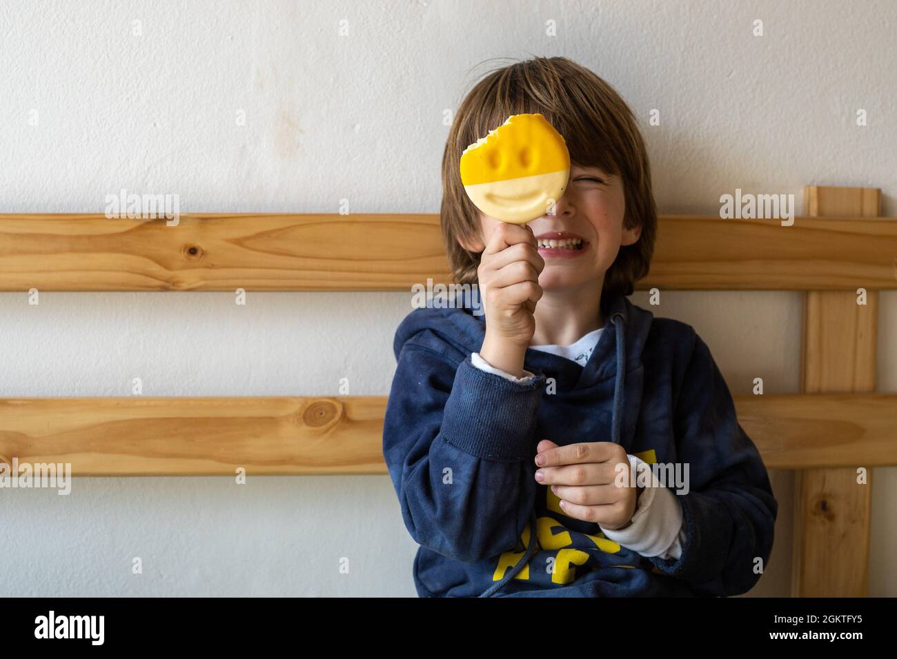 Closeup of a little boy smiling and covering his face with a lollipop ...