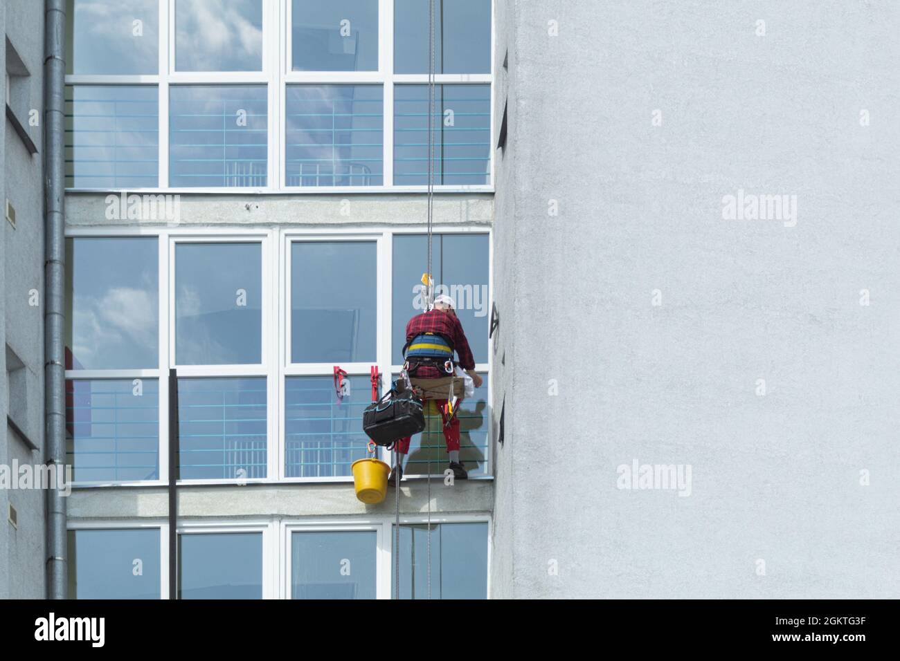 A man washes windows in a multi-storey building. Professional window ...