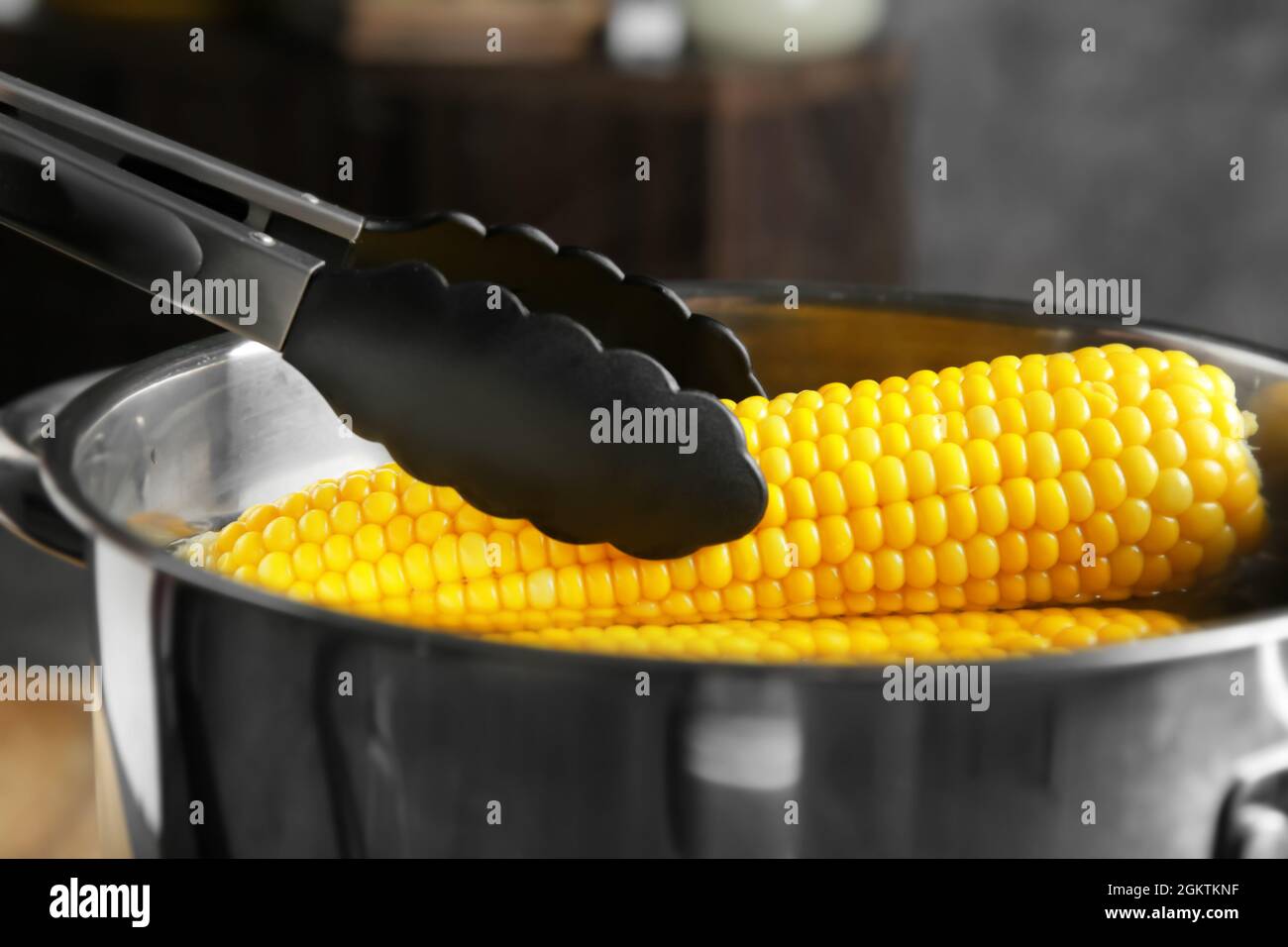 Tongs taking out corn cob from saucepan Stock Photo - Alamy