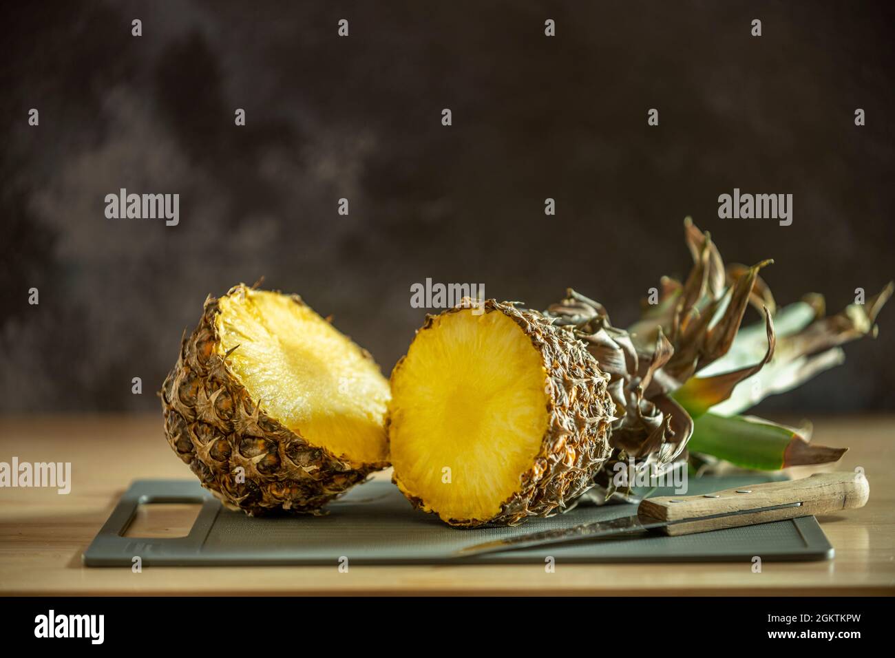 Ripe pineapple cut in half with a kitchen knife with wooden scales ...