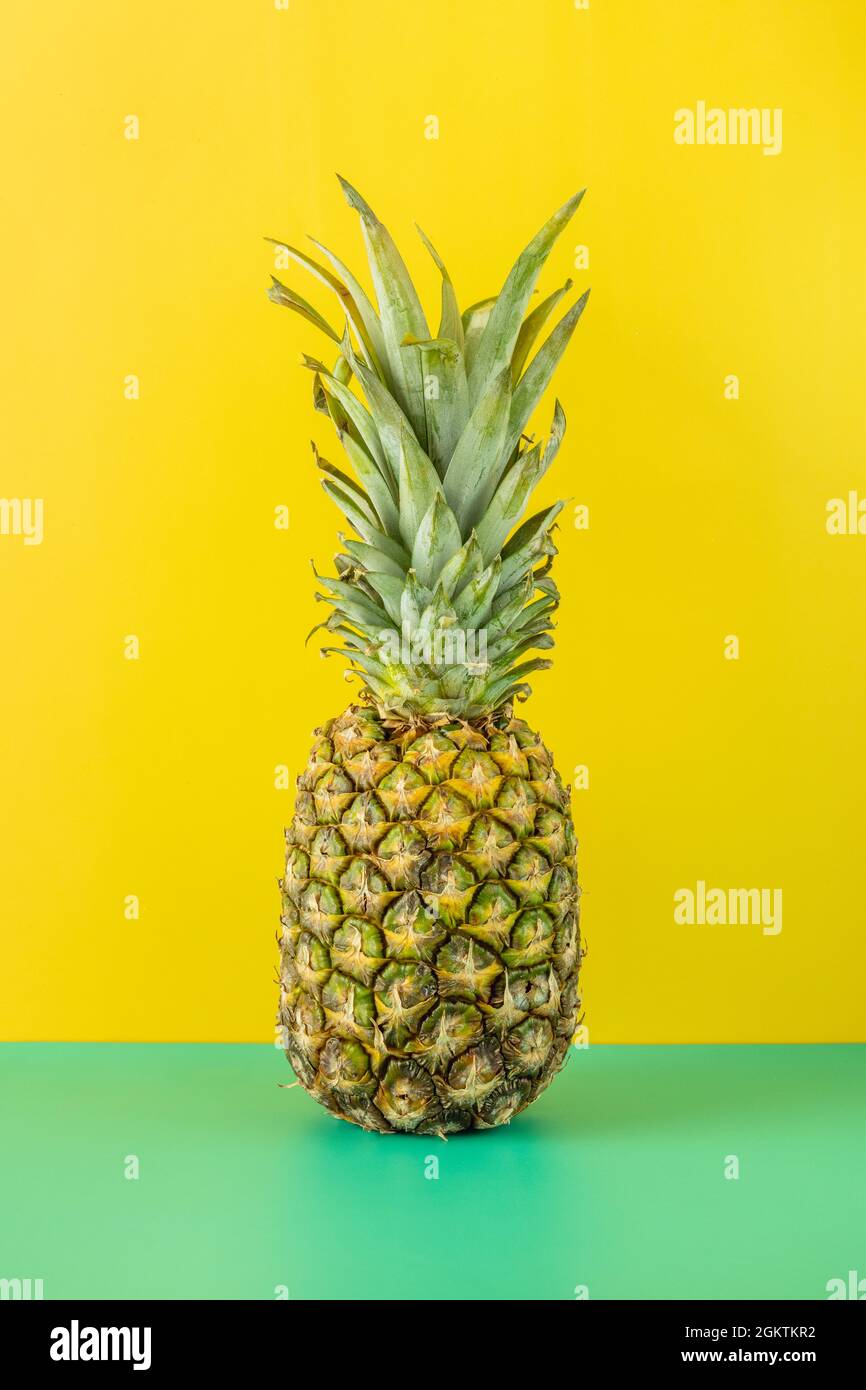 Ripe pineapple on plain green table and bright yellow background Stock ...