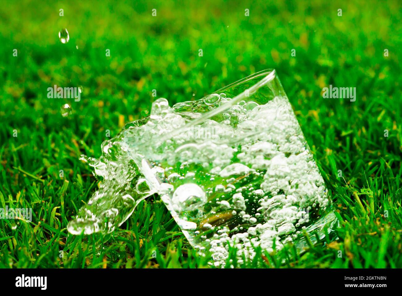 A falling glass of water or lemonade on grass background. Water with ...