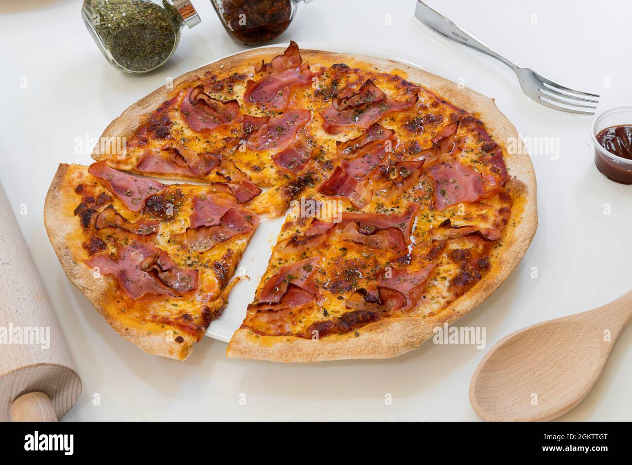 Italian thin crust pizza with lots of bacon and cheese with a cut piece ...
