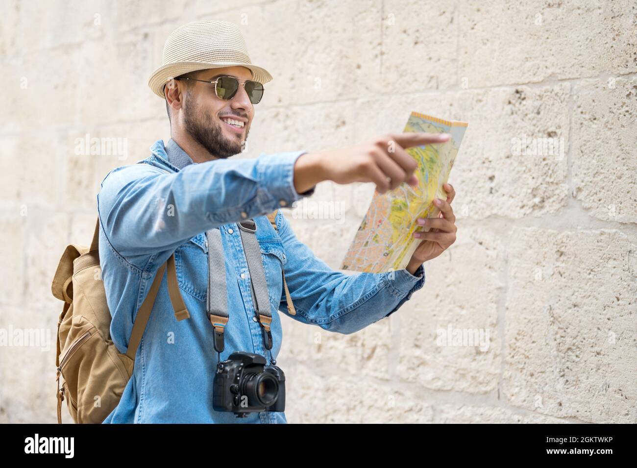 Handsome tourist man look at map while pointing finger in the direction ...