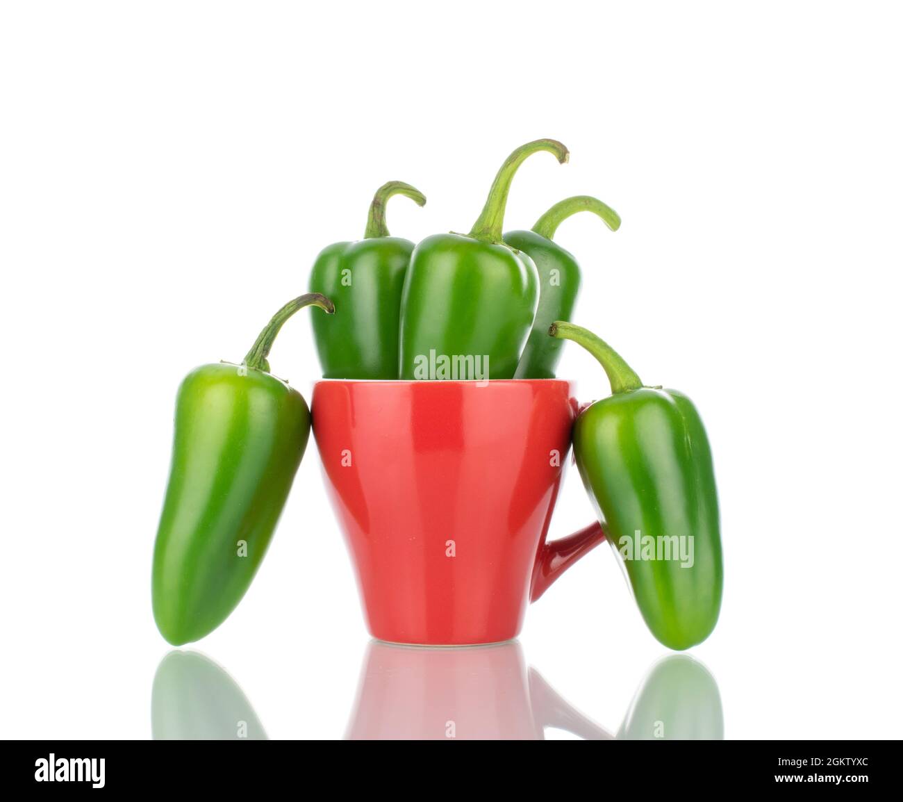 Several green spicy pepper pods with a red ceramic cup, close-up ...