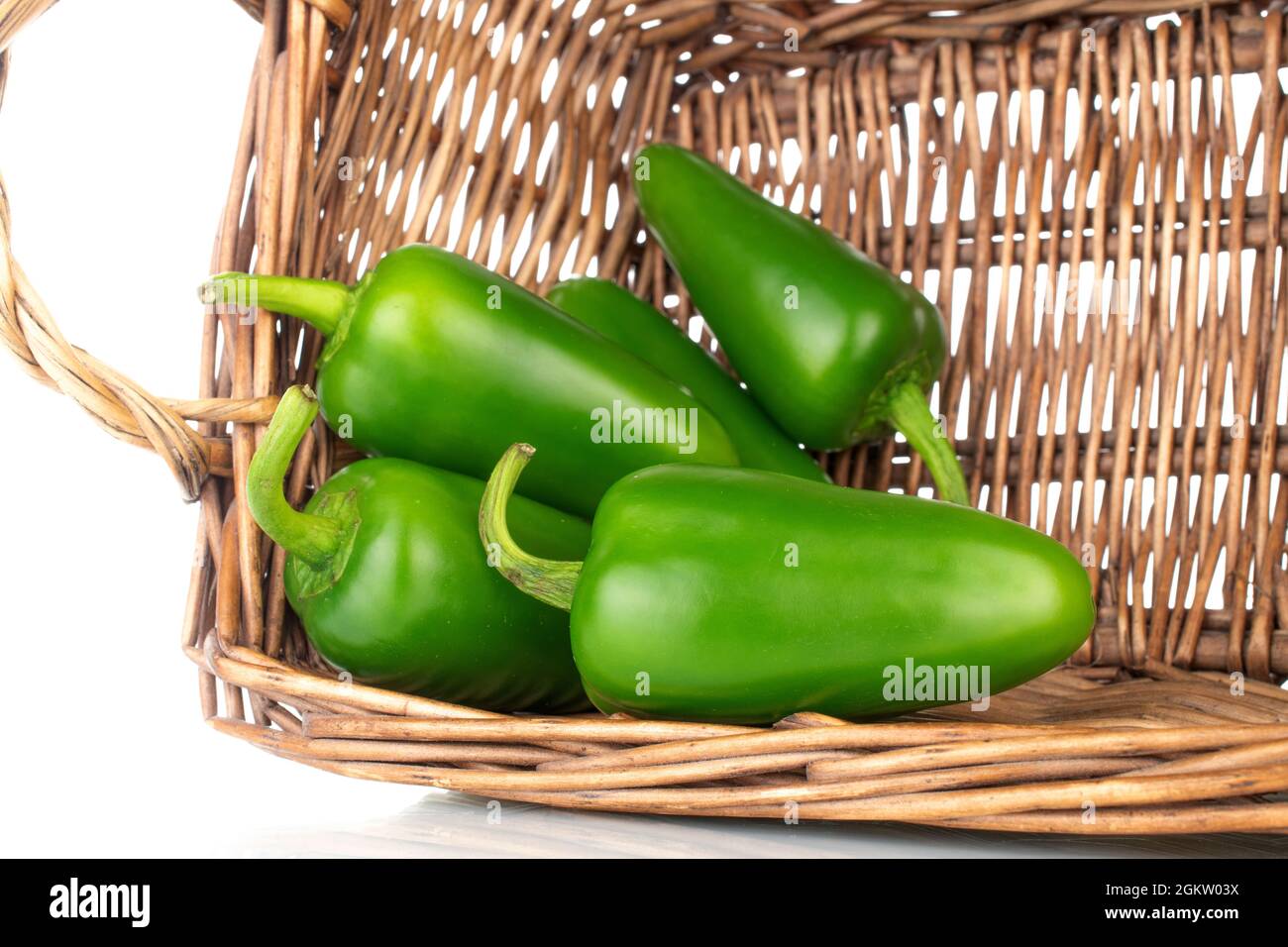 Several green spicy pepper pods with a basket, close-up, isolated on ...