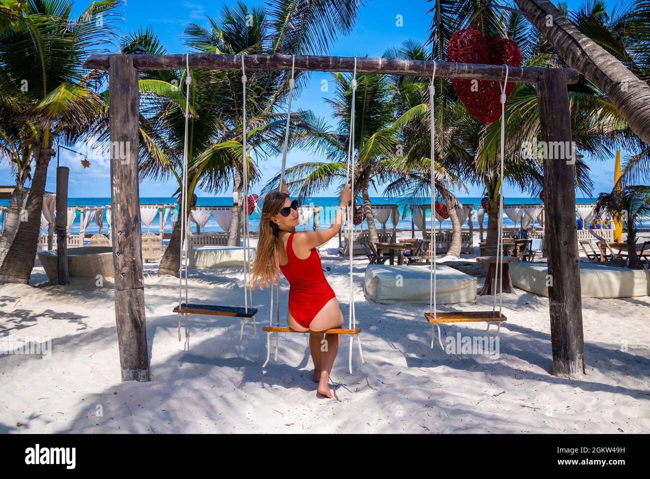 Woman in swimsuit sitting on wooden swing seat at beach resort Stock ...