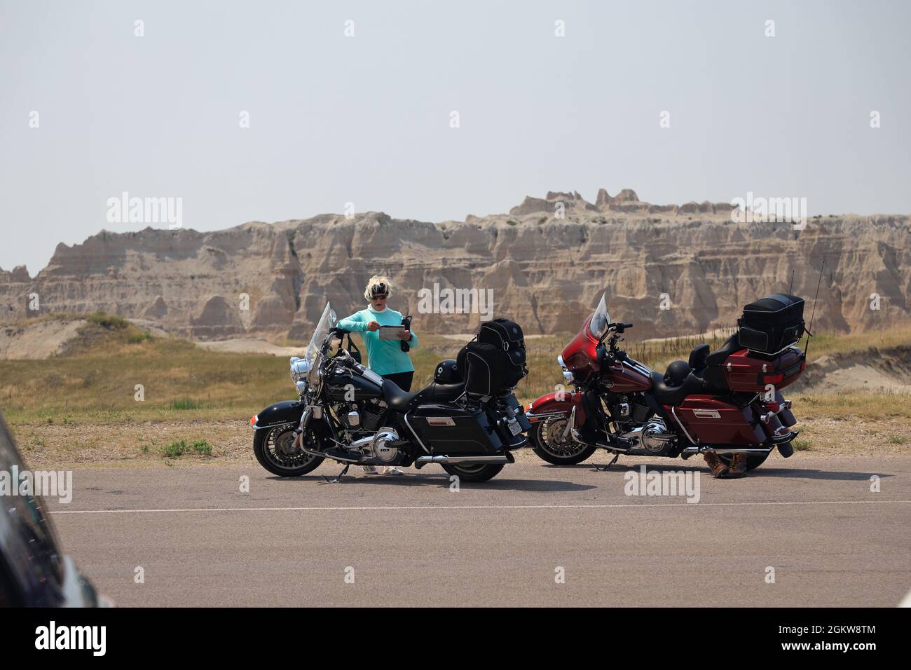 A female biker reading a map beside her motorcycle in Badlands National ...
