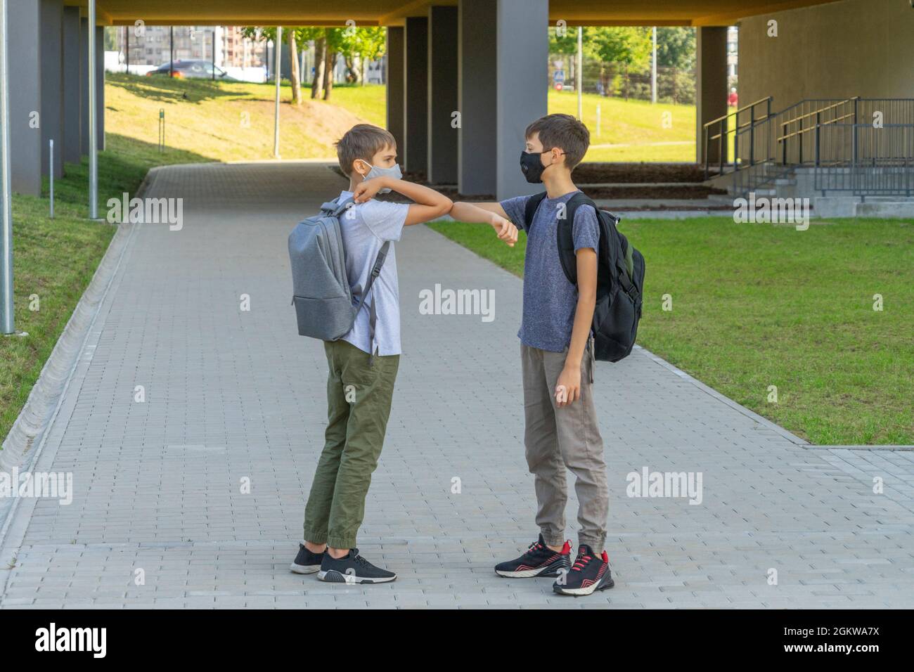 Elbow bump greeting. Two teenage boys with protective mask and ...