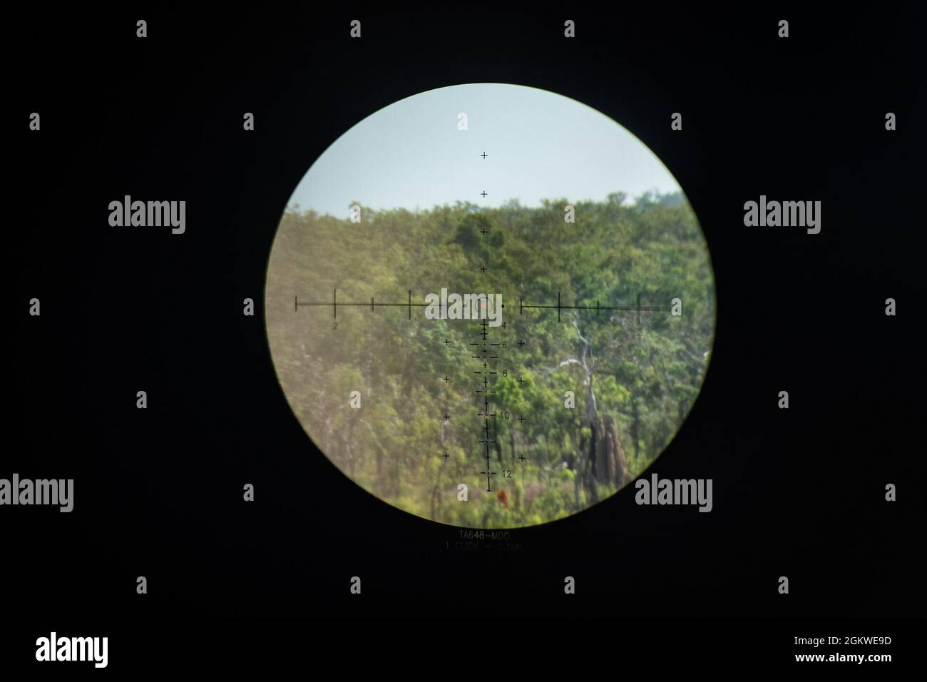 An optic of an M240B machine gun is shown pointing towards a designated ...