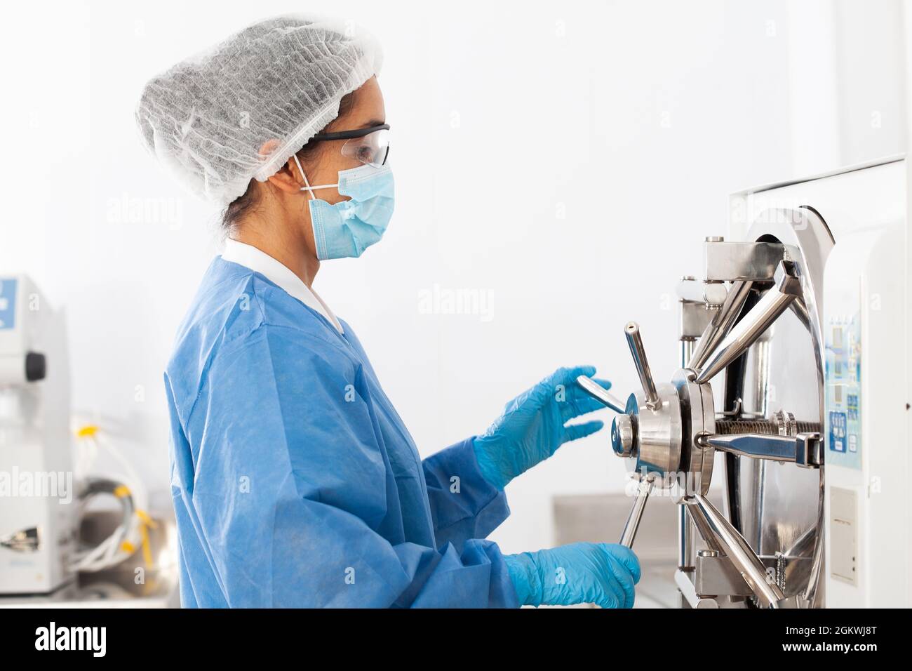 Young female scientist sterilizing laboratory material in autoclave ...