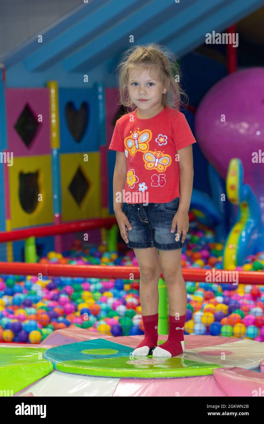 Happy caucasian little girl of five years old standing in play center ...