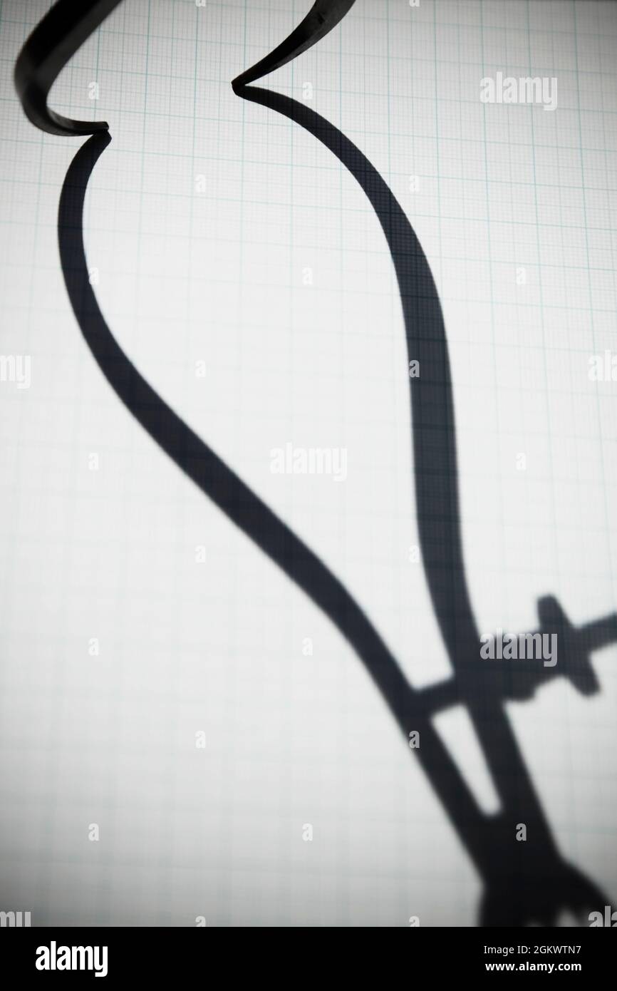 Metal outside spring calipers casting abstract shadow on piece of graph ...
