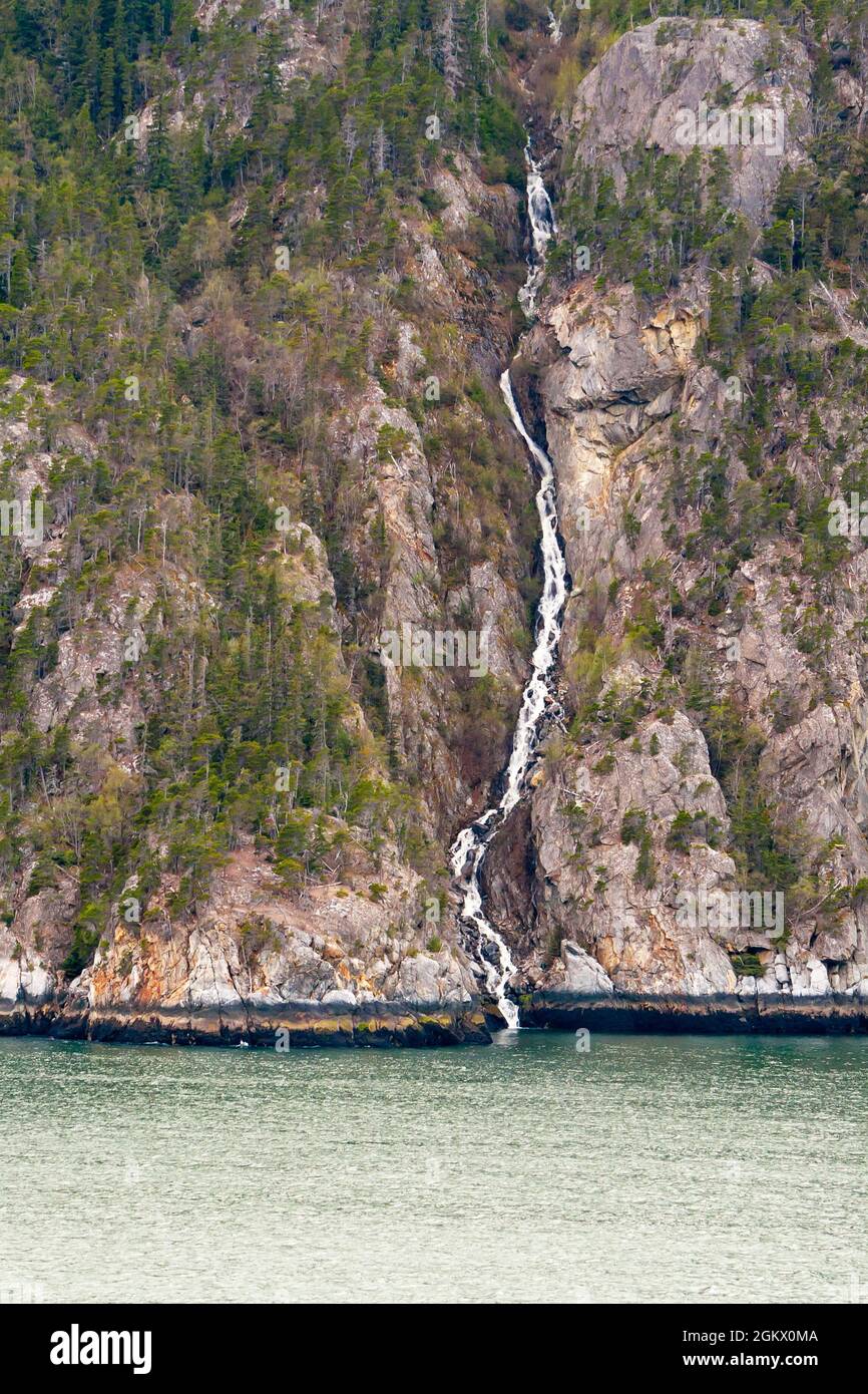 A waterfall flowing down a mountainside into the ocean along the Inside ...