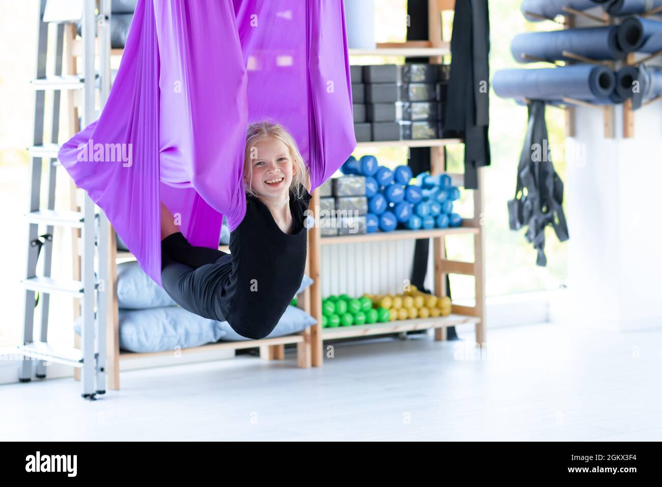 Portrait young smiling girl practice in aero stretching swing in purple ...