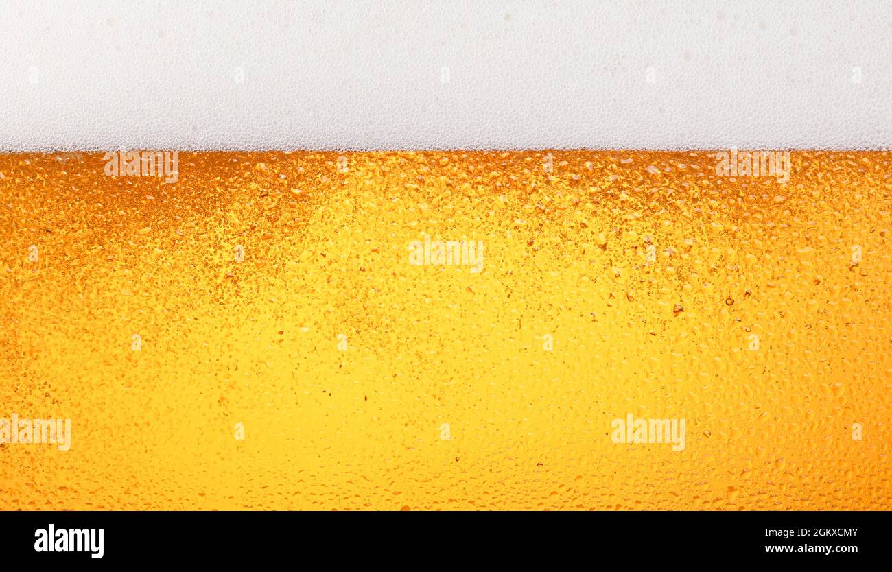 Close up background texture of pouring lager beer with bubbles and ...
