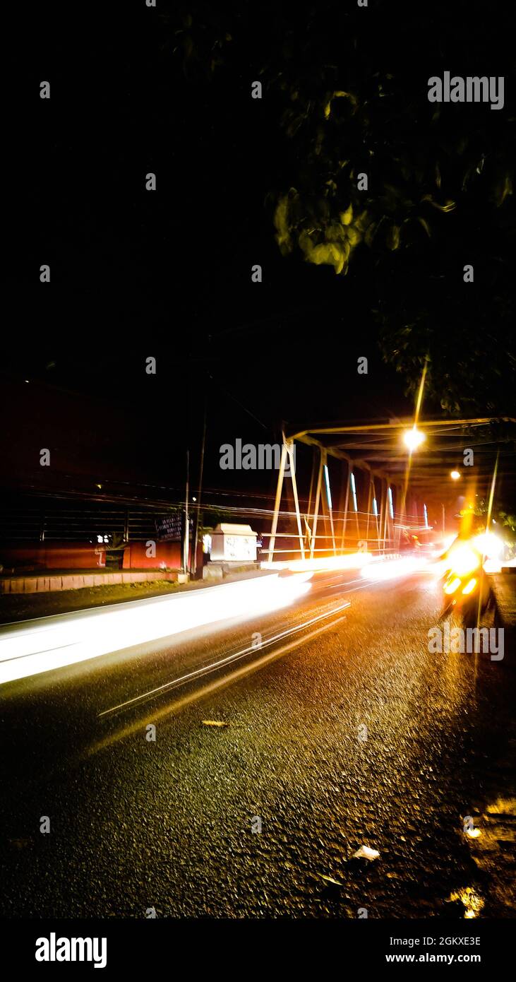 Vertical shot of cars driving on a road with long exposure at night ...