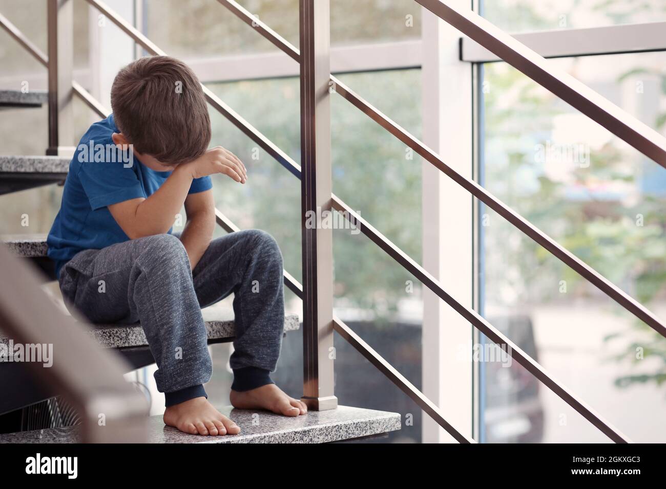 Little boy crying on stairs indoors. Domestic violence concept Stock ...