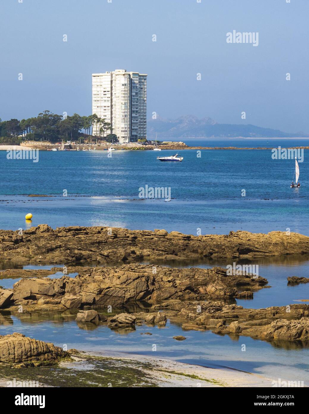 Vertical shot of a rocky seashore with a building in the background ...