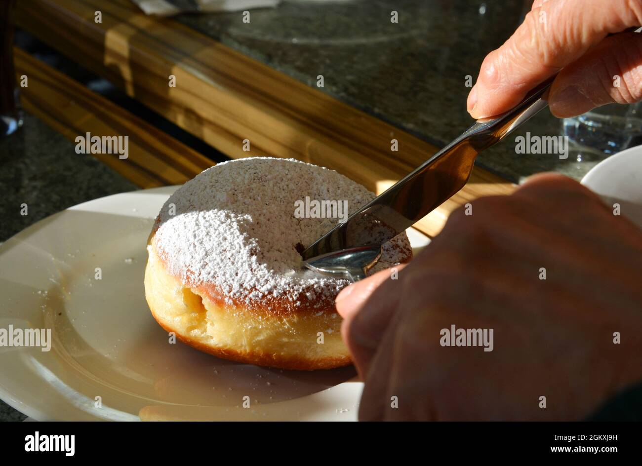 Cutting into a doughnut for afternoon tea Stock Photo - Alamy