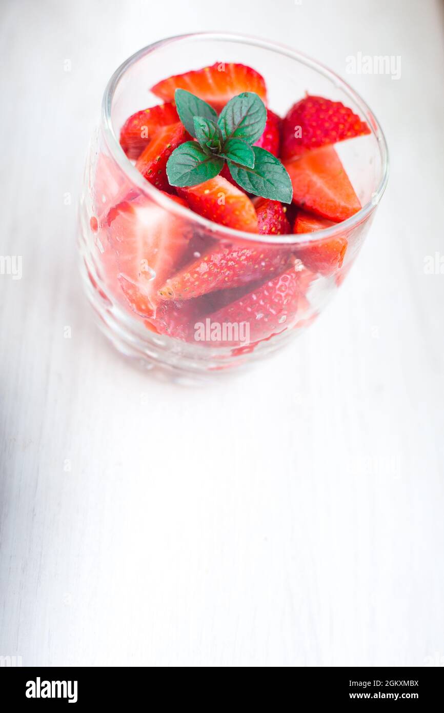 Glass with pieces of red strawberry and fresh peppermint leaves on top ...