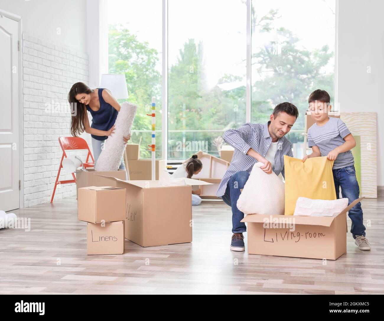 Happy family unpacking moving boxes in room at new home Stock Photo - Alamy