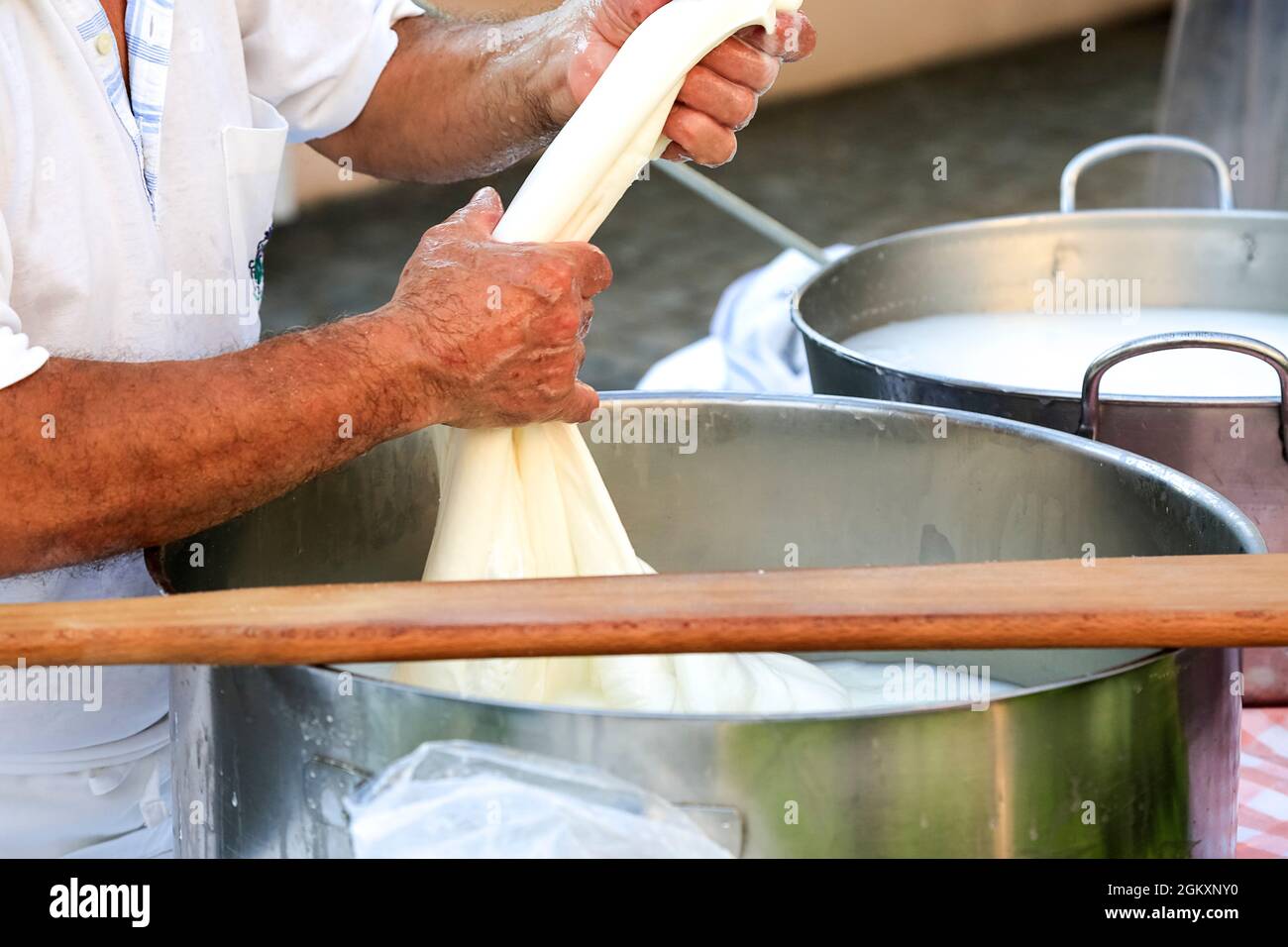 Man cooks mozzarella di bufala in big metal vat in cheese dairy. Human ...