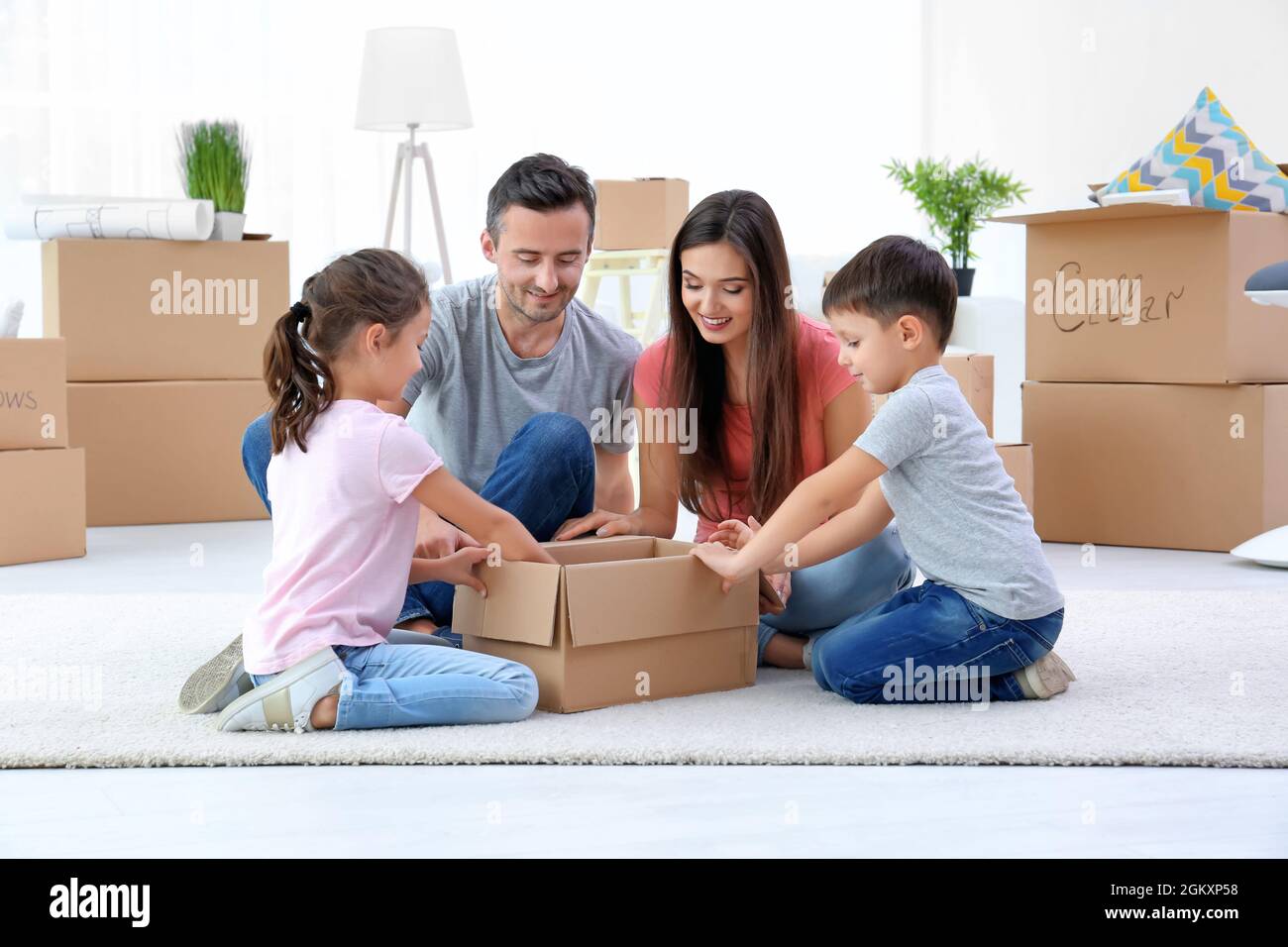 Happy family unpacking moving boxes in room at new home Stock Photo - Alamy