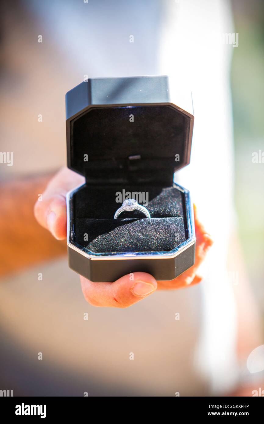 Wedding ring with diamonds in black elegant box. Man holds an open ...
