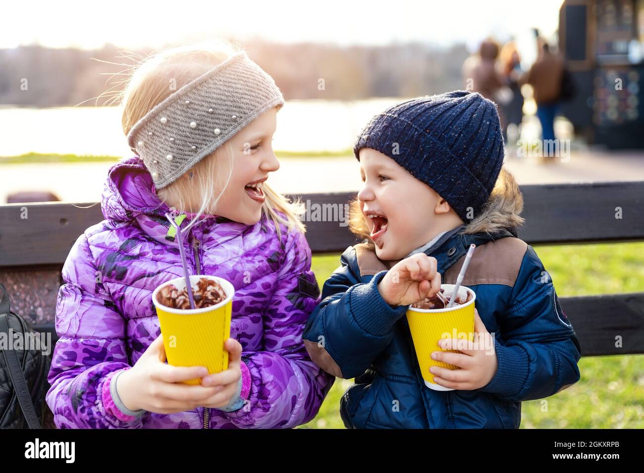 Two cute adorable siblings children sitting on bench drink delicious ...
