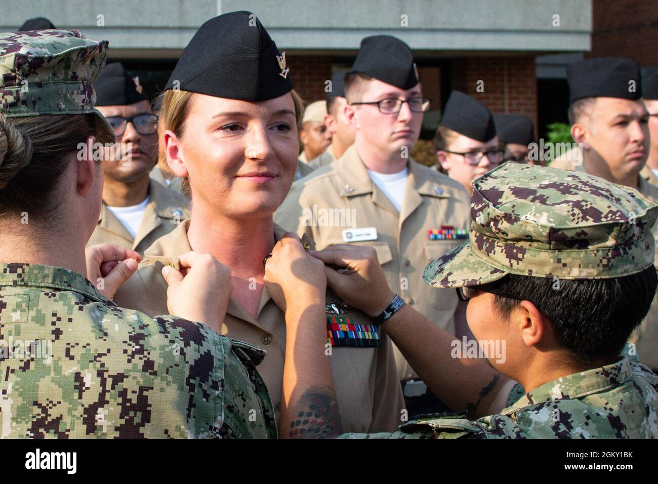 Two sailors pin the rank of Petty Officer Second Class upon Altaira ...
