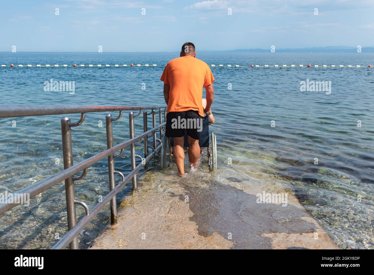 Disabled man on a wheelchair being transported into sea for swimming ...