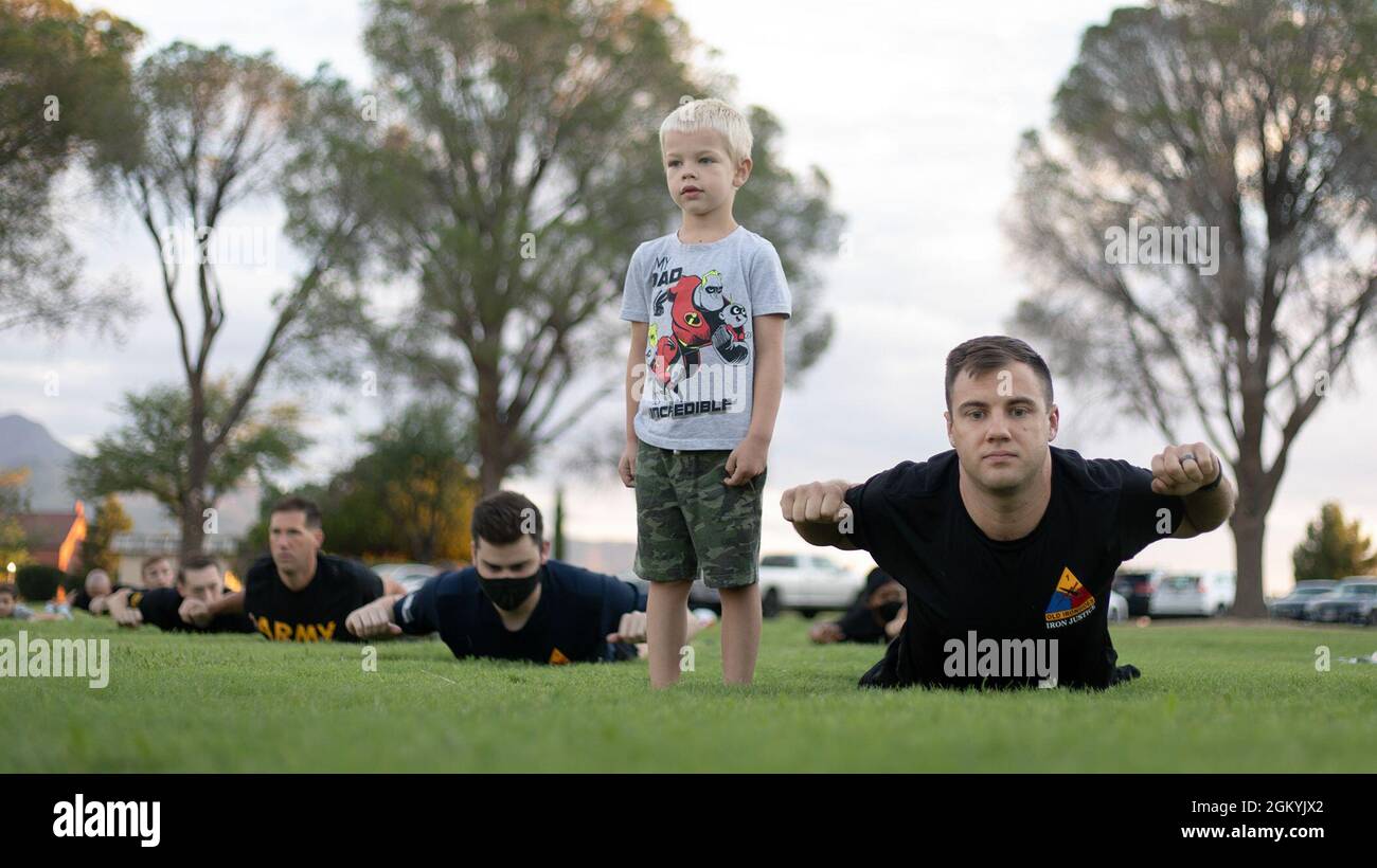 An Army kid looks on as his dad and teammates warm up before morning PT ...