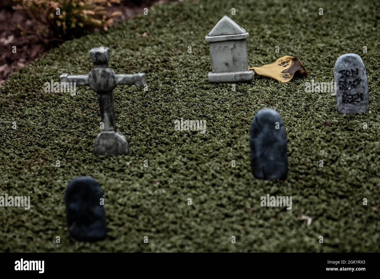 Low-saturation closeup of tiny model gravestones in a graveyard at a ...