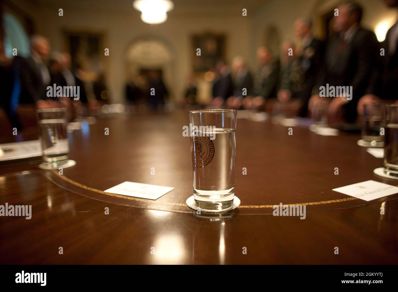 A glass of water with the presidential seal rests on the table in the ...