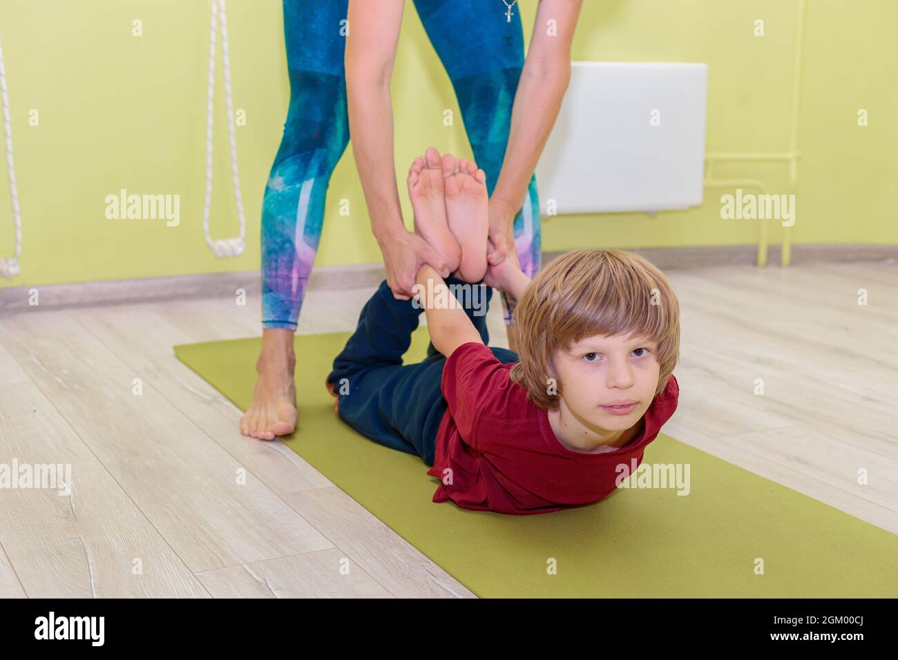 A woman instructor in a sports uniform is engaged in yoga with a boy ...