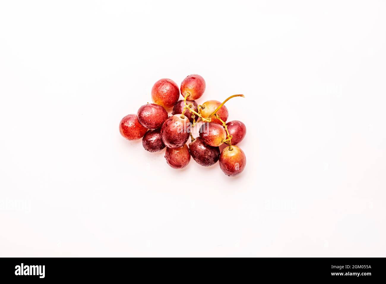 Small bunch of light red grapes viewed from the top on white background ...