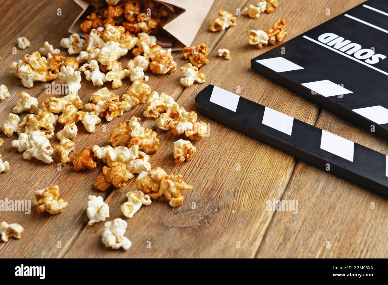 Caramel popcorn and movie clapper on wooden background Stock Photo - Alamy
